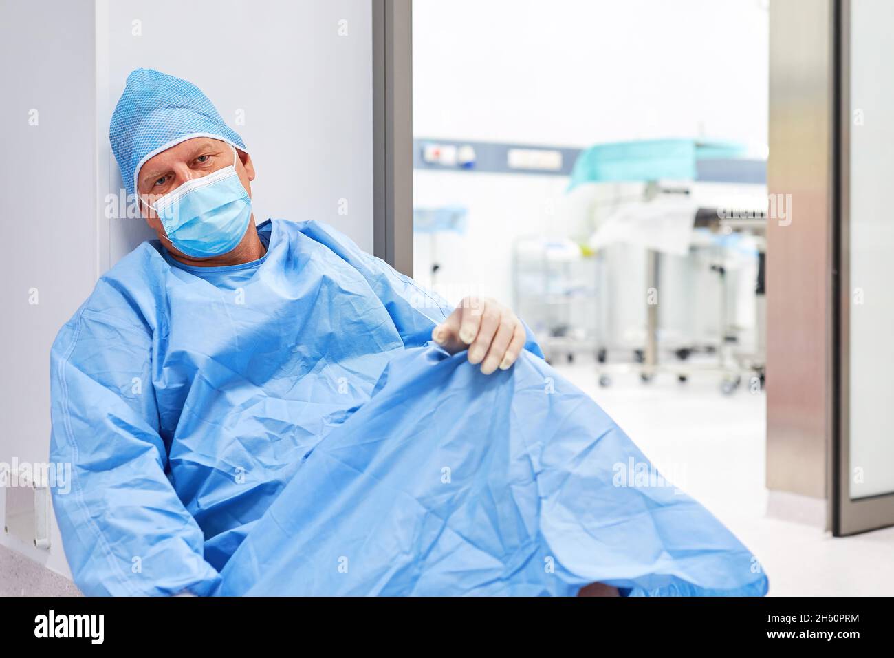 Clinic doctor in protective clothing sits completely exhausted and ...