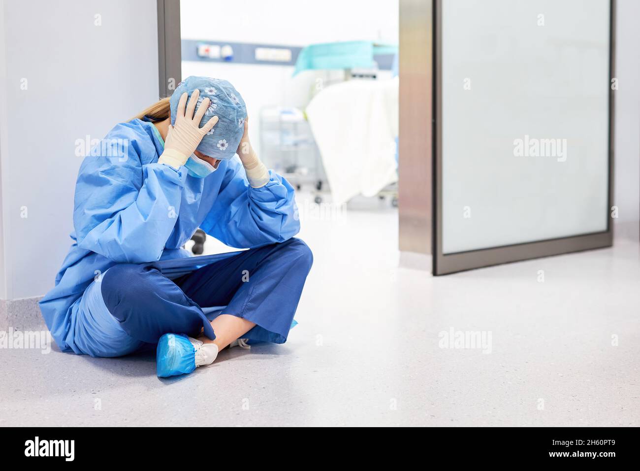 Exhausted doctor or nurse sits in front of the operating room due to ...