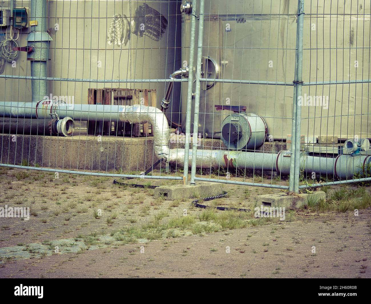 Metal fence around an industrial facility with pipes Stock Photo - Alamy