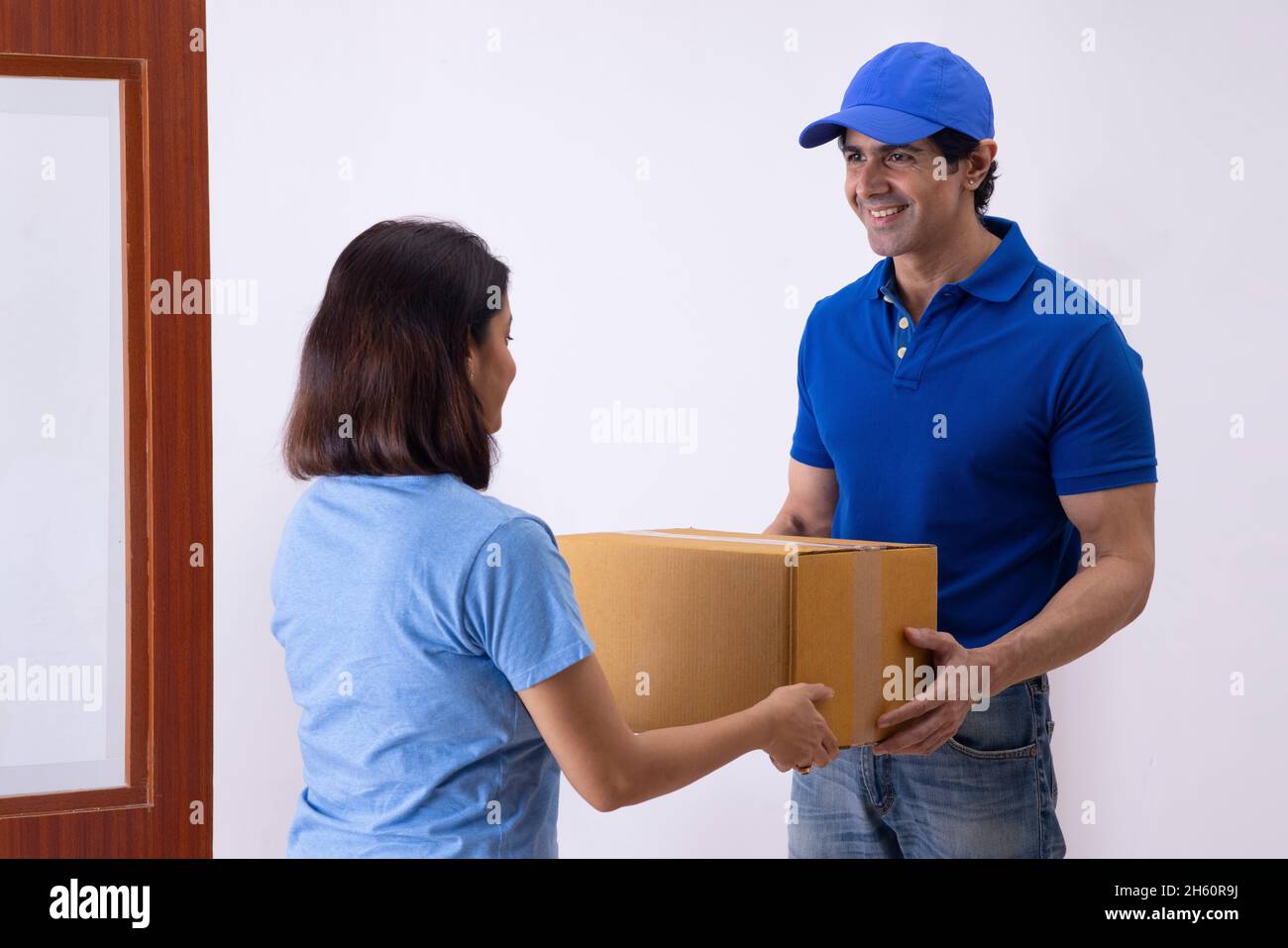 Indian woman accepting parcel from delivery boy at home Stock Photo - Alamy