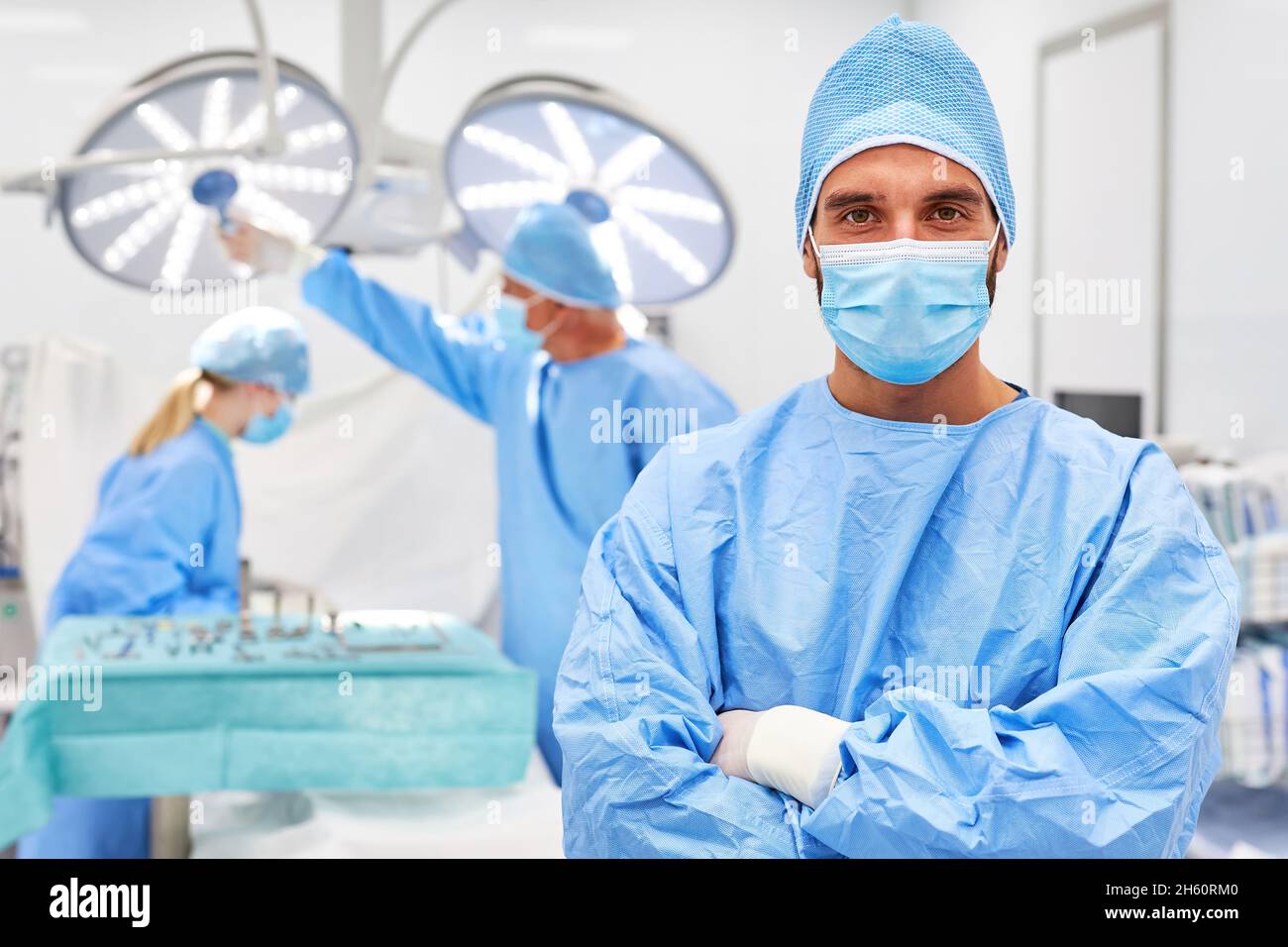 Young surgeon with crossed arms in front of his surgery team in the ...