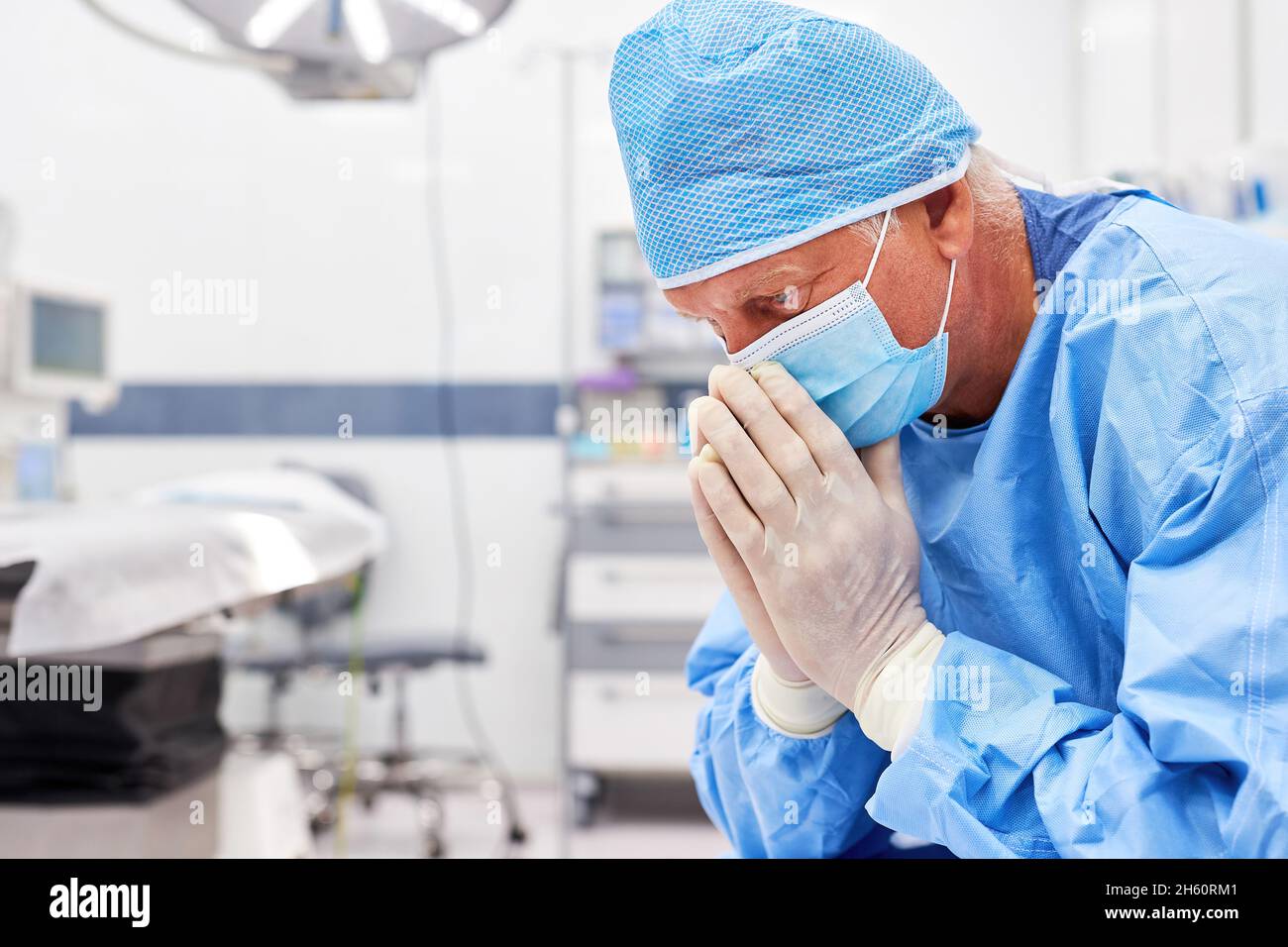 Exhausted and worried surgeon sits in the operating room after a ...