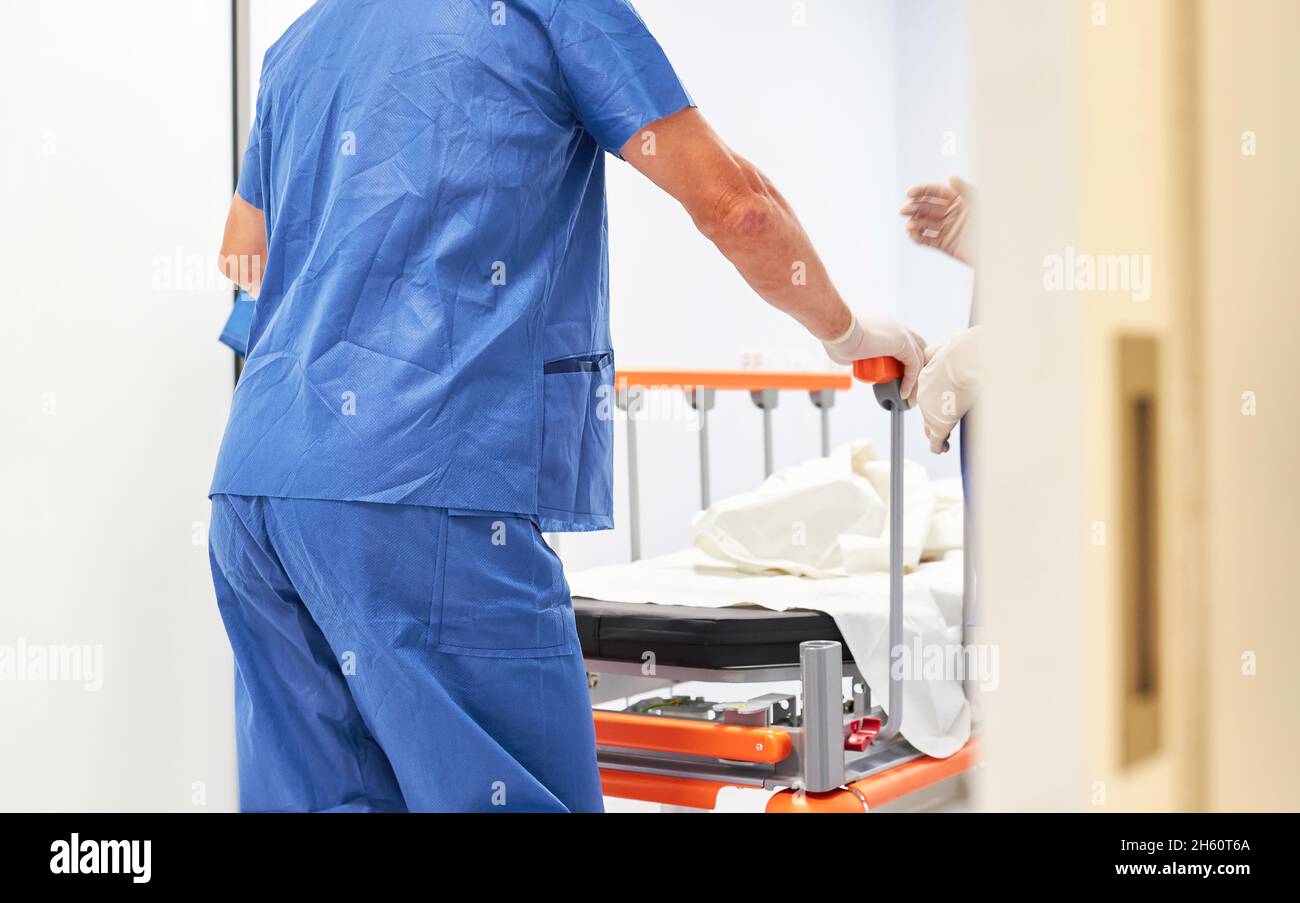 Male nurse pushes hospital bed with patient in hospital corridor before ...