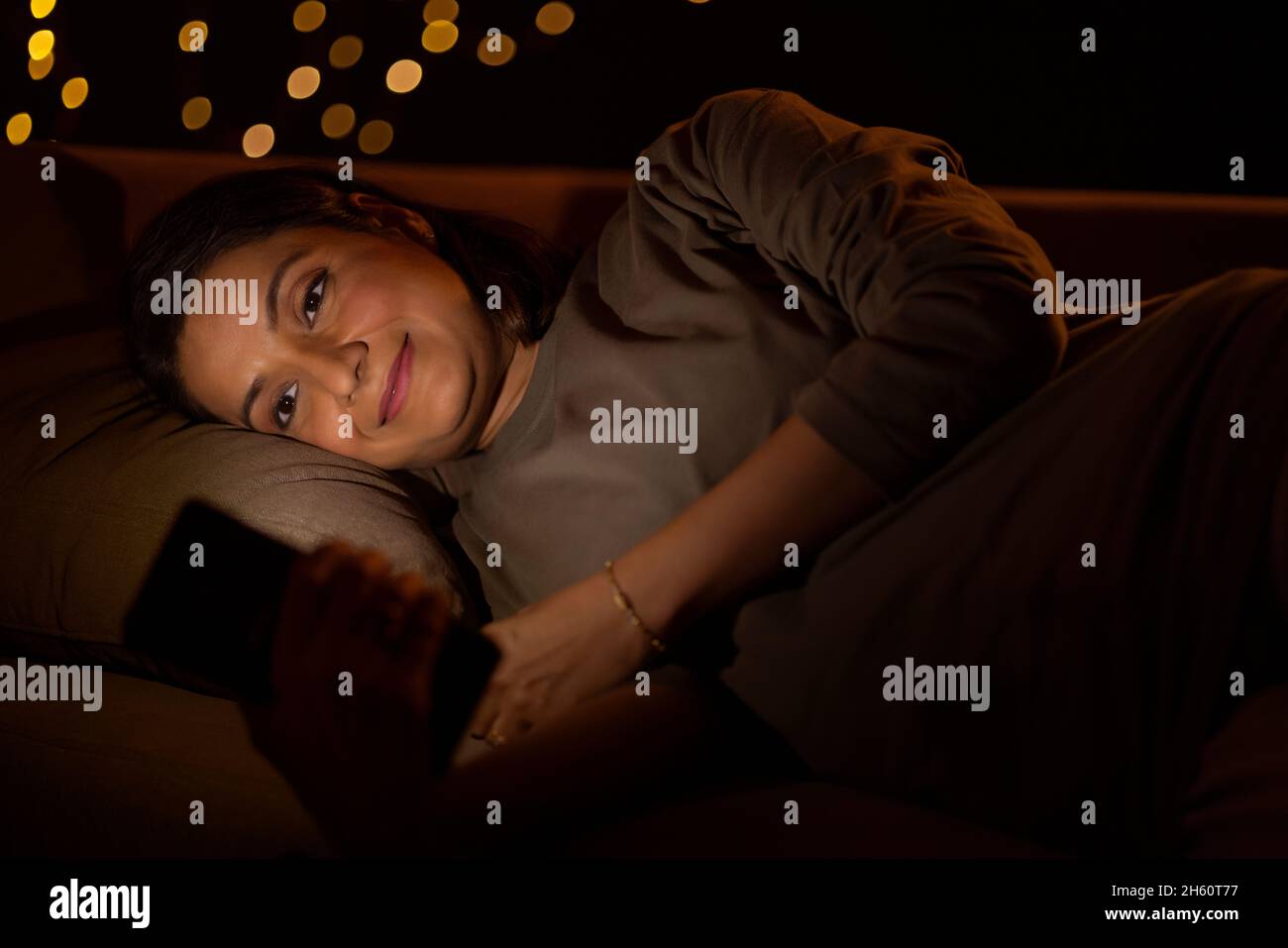 Indian woman watching smartphone at night while lying on bed Stock ...