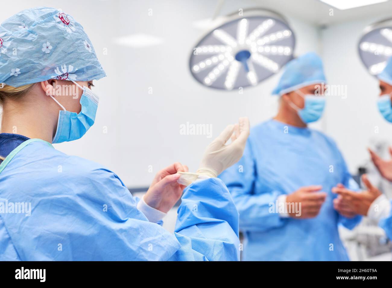 Young woman as a surgeon puts on disposable gloves in preparation for ...