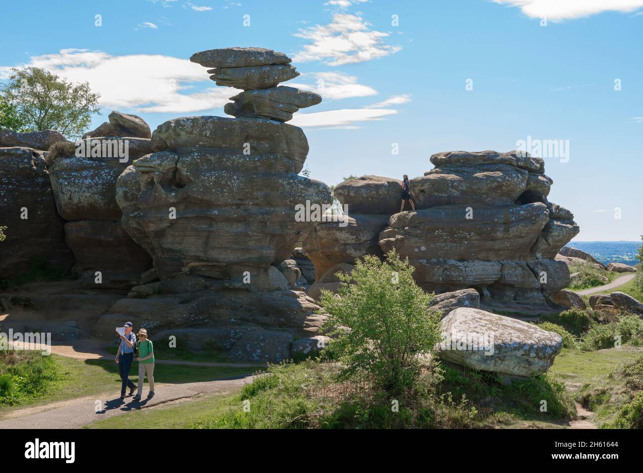Brimham Rocks, view in summer of a senior couple walking past a heavily ...