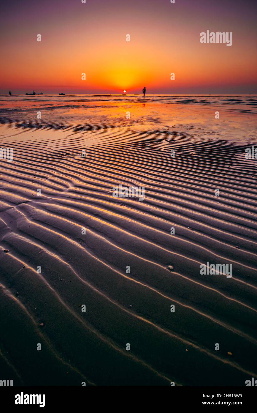 Vertical shot of the beach at sunset and people walking. Larnaca ...