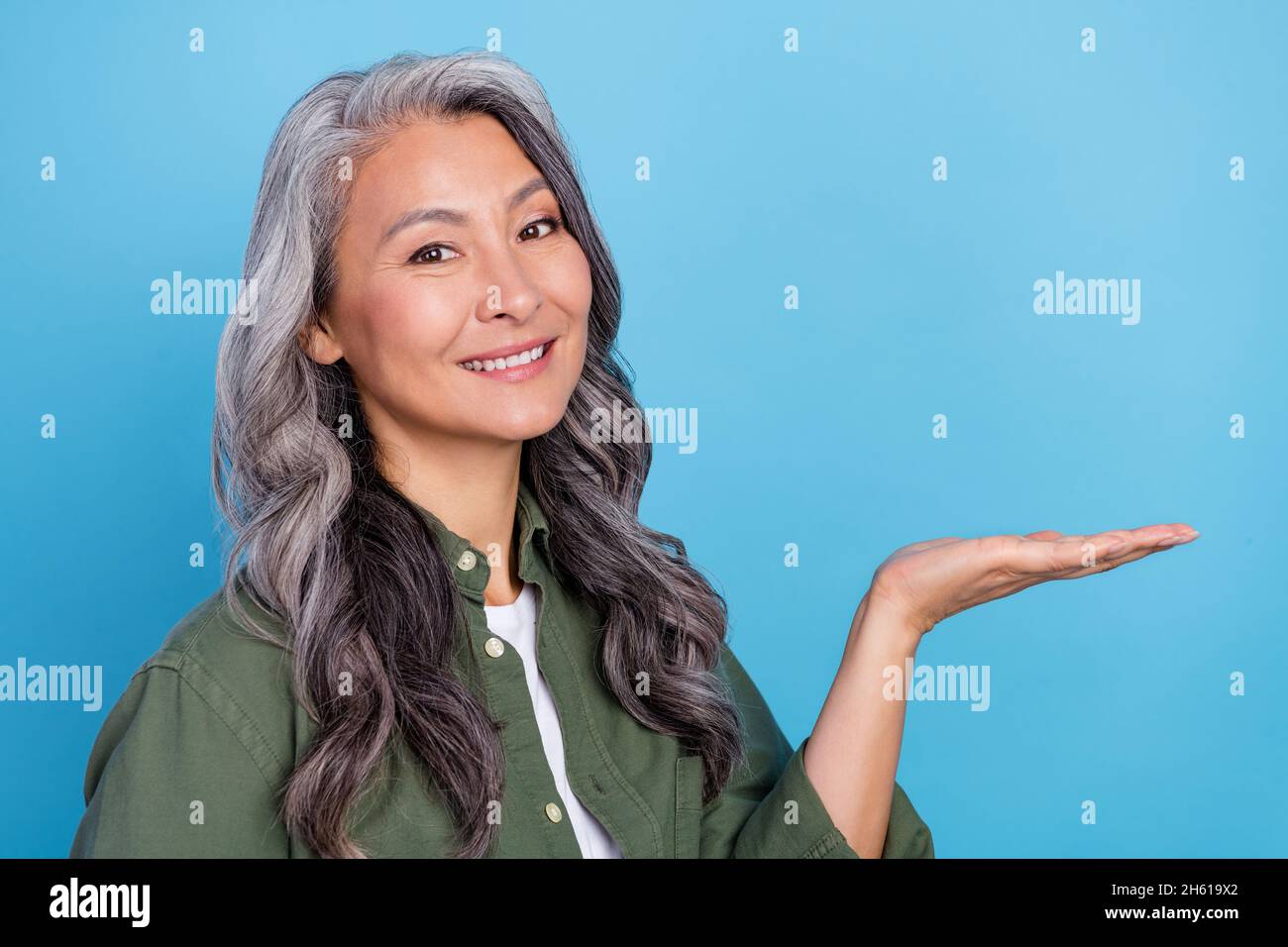Photo of cute elder grey hairdo lady hold empty space wear green shirt ...