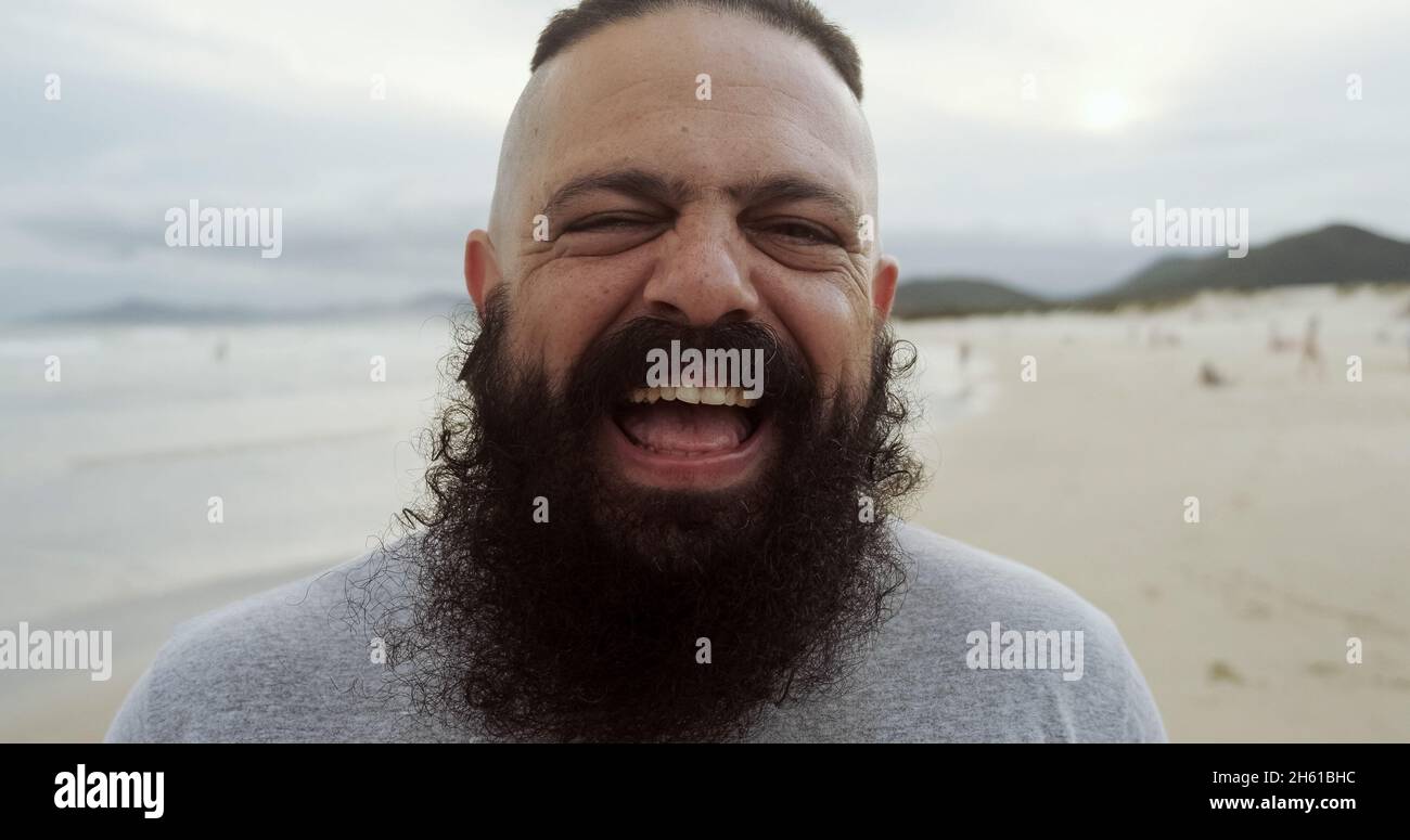 Happy latin man with big beard on a beach looking at camera and smiling ...
