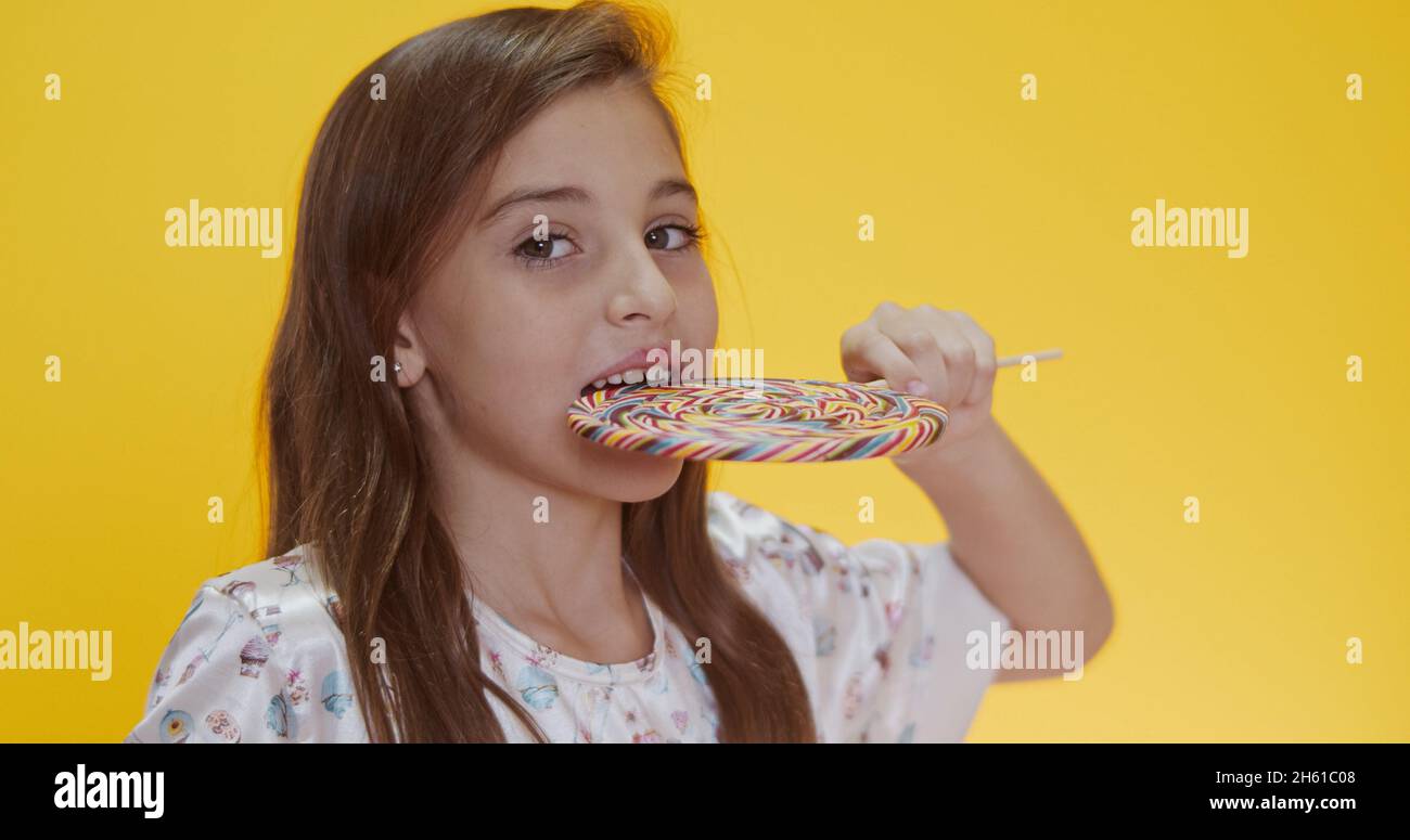 Happy child sucking lollipop on yellow background Stock Photo - Alamy