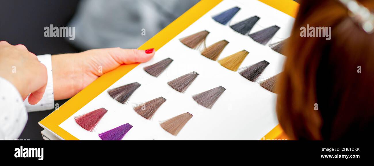 Young caucasian woman choosing a color from the hair color chart in a ...