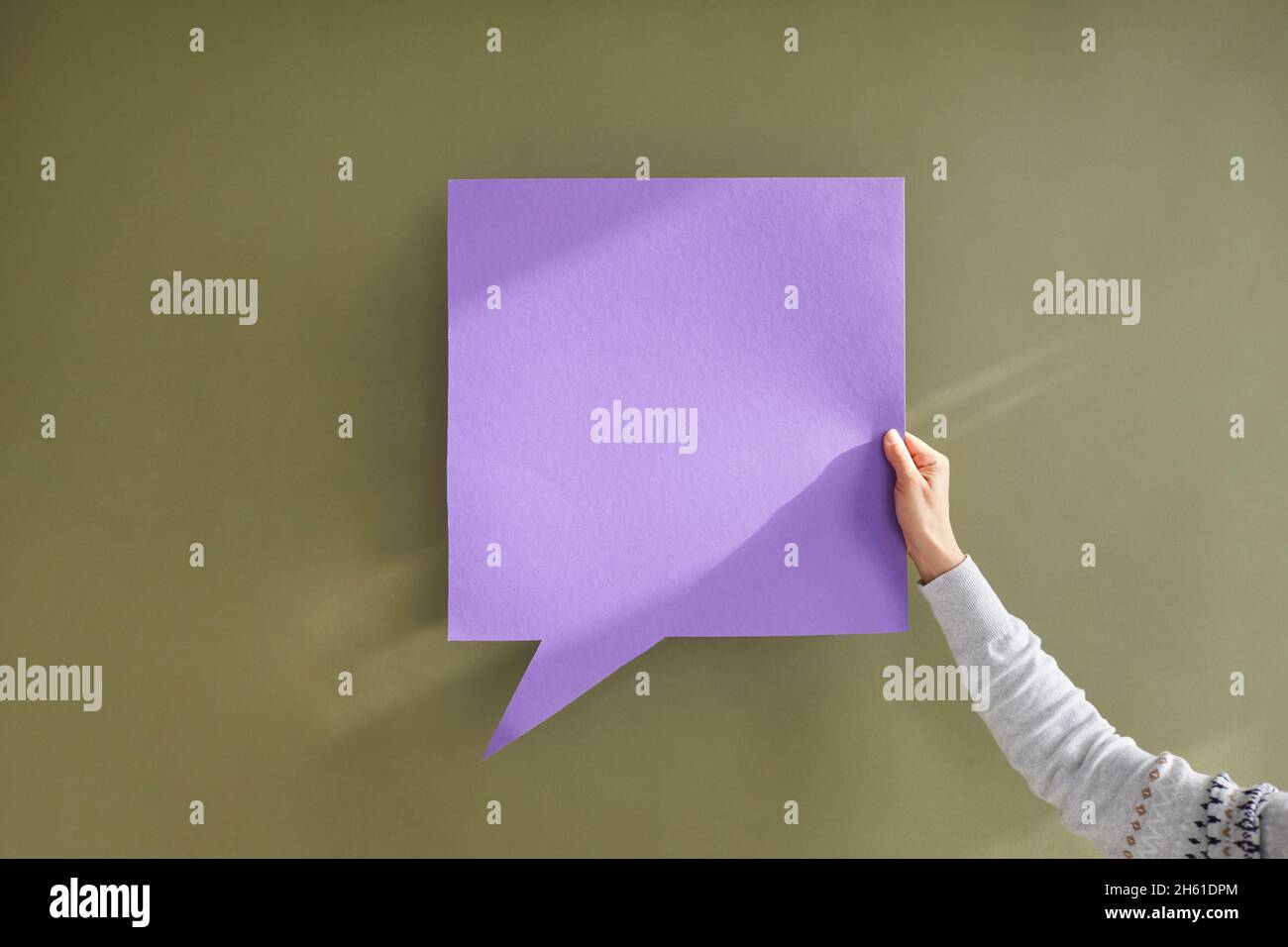 Anonymous person holding purple square mockup message bubble on green ...