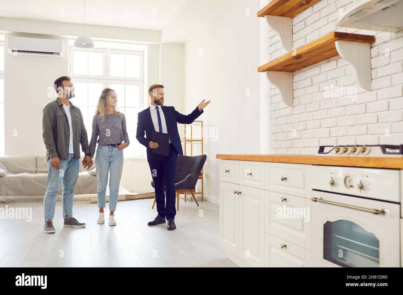 Real estate agent giving his clients tour about all rooms in new house ...