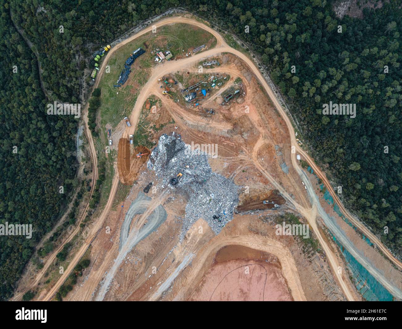 Top view of a dump landfill with garbage surrounded by a forest with ...