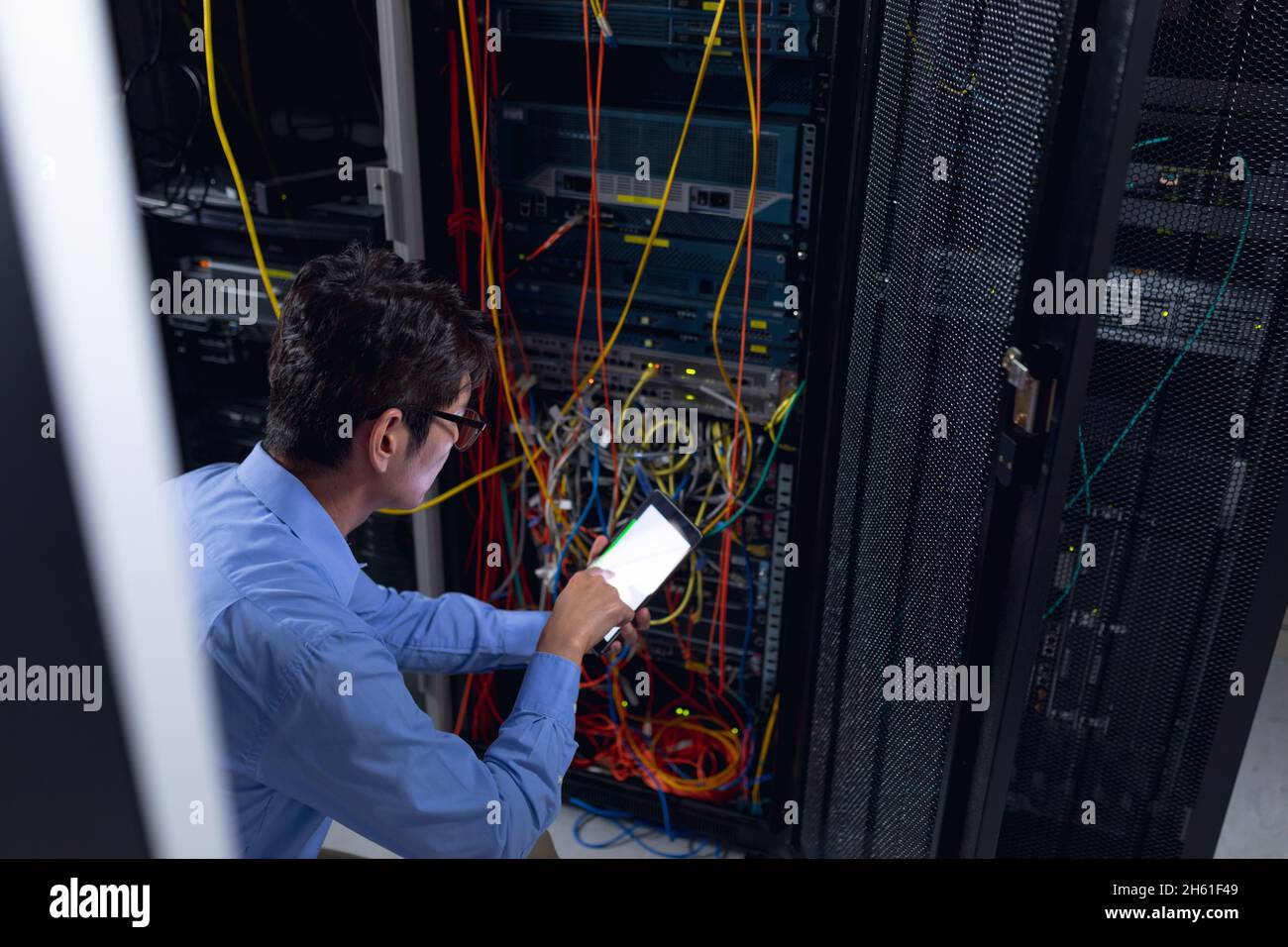 Asian Male Engineer Using Digital Tablet And Inspecting Computer Server In Computer Server Room