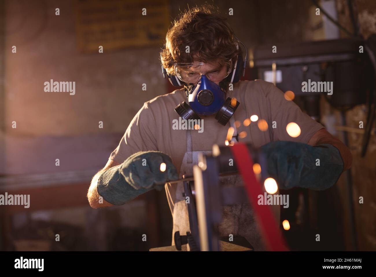Blacksmith wearing gas mask while working on metal in manufacturing ...