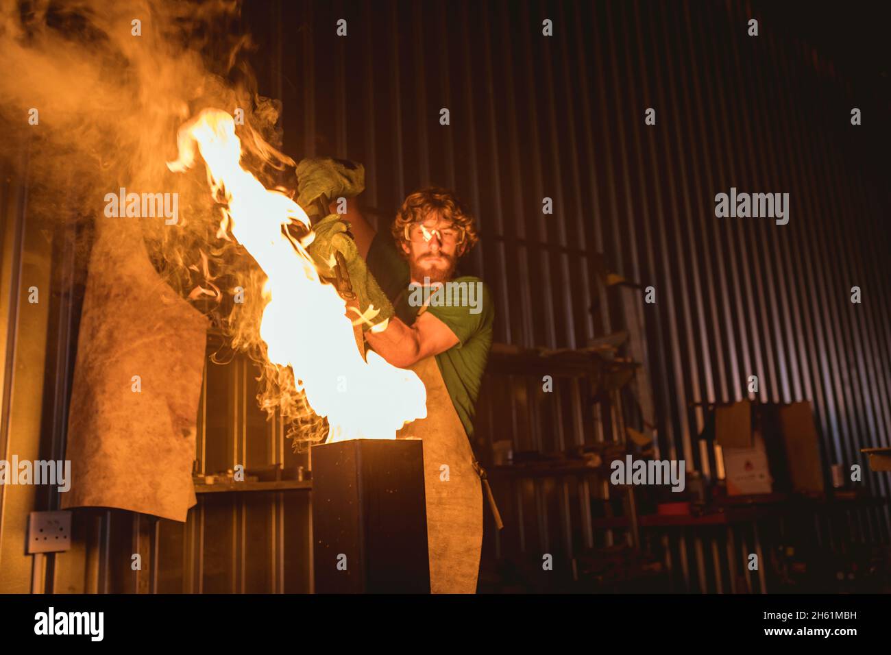 Blacksmith putting metal in fire while forging in manufacturing ...