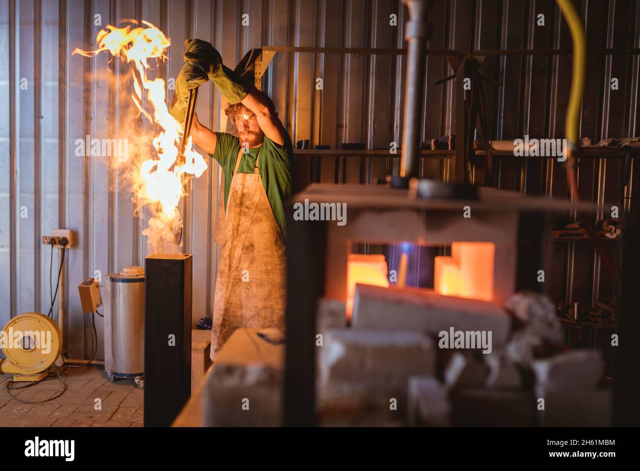 Caucasian blacksmith putting metal in fire while forging in ...