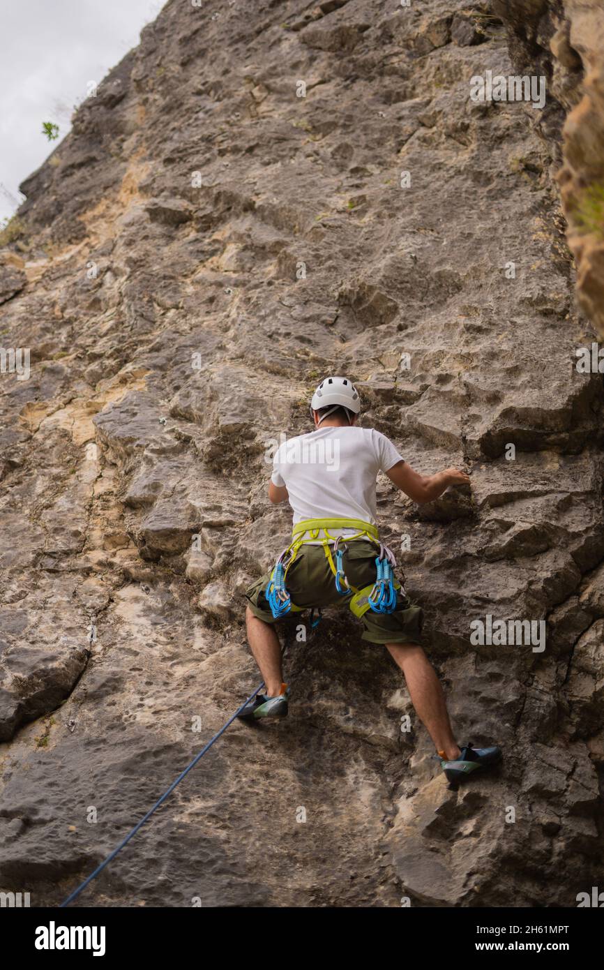 Handsome and fit young guy is climbing the hill while wearing the whole ...