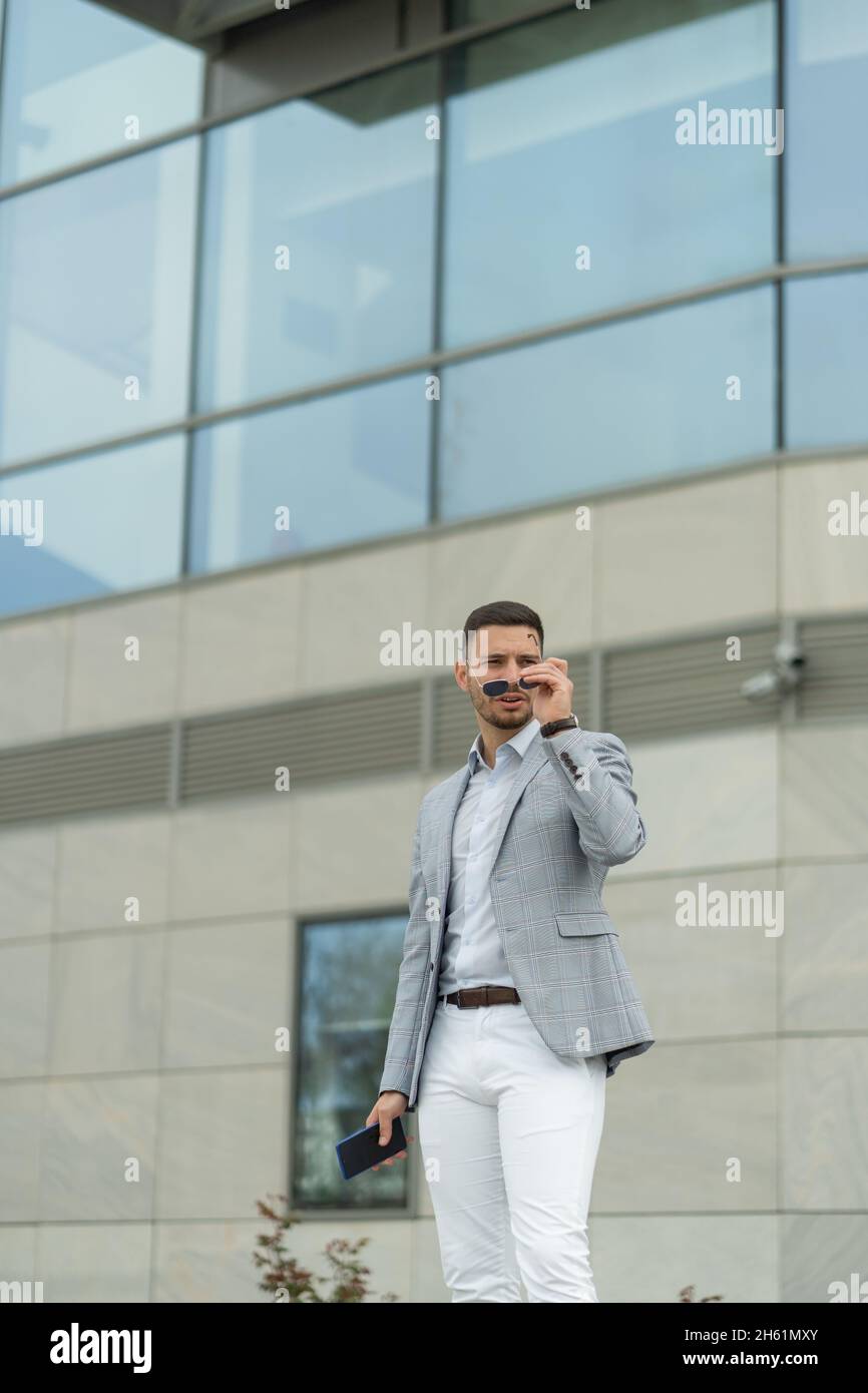 Urban businessman is putting his sunglasses on while he is thinking ...