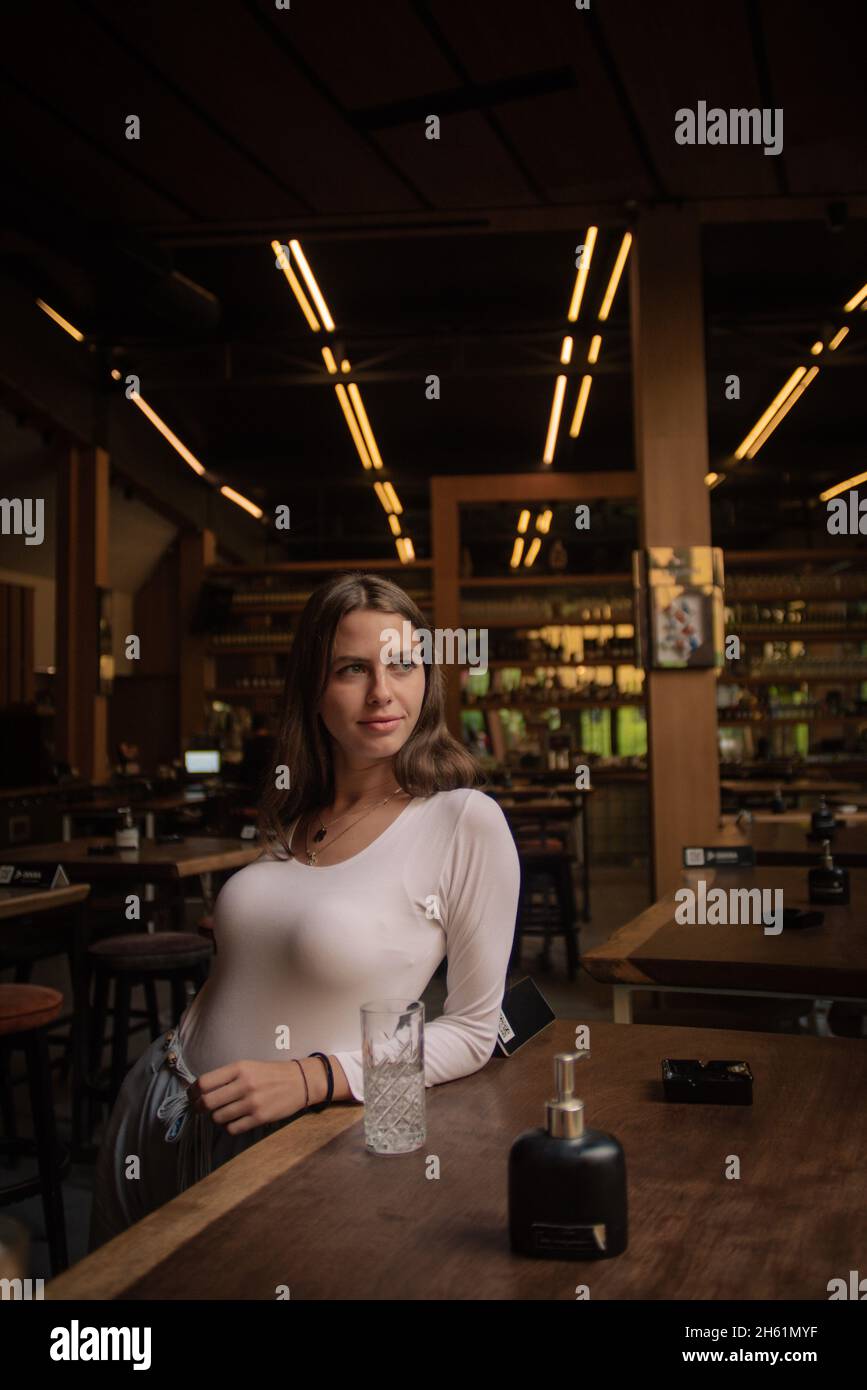 Attractive and beautiful girl is posing while leaning on the table in ...