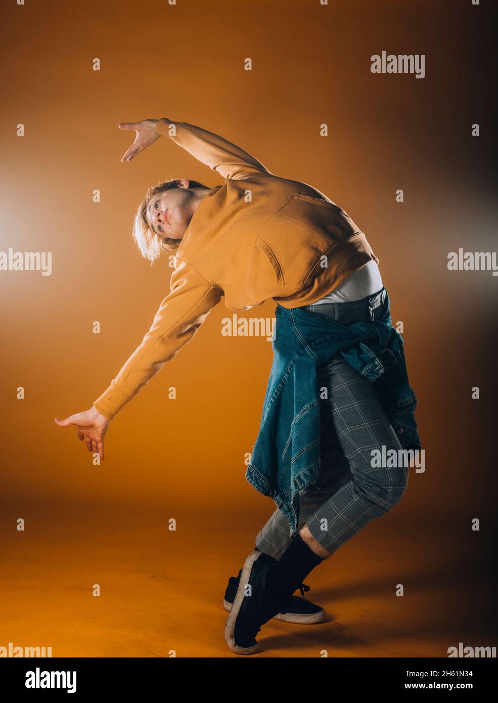 Muscular male dancer performing a dance routine in the orange studio ...
