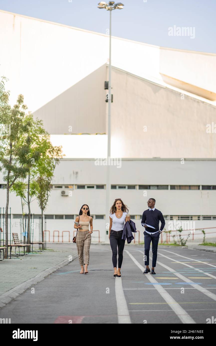 Three multiracial business partners are looking around while walking ...