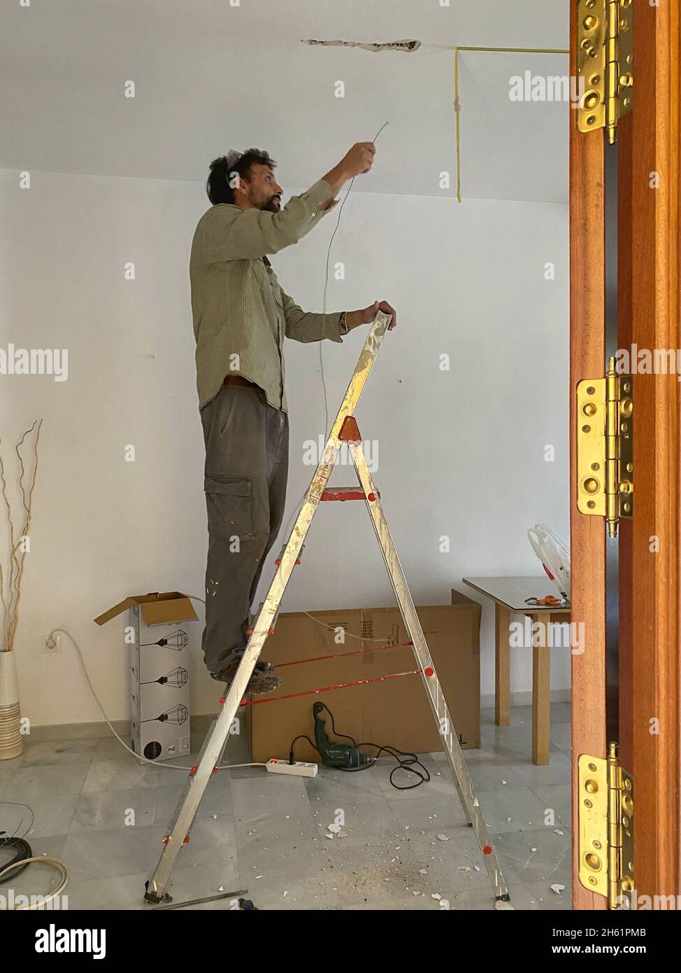 Caucasian male fixing electricity wires in a white wall Stock Photo - Alamy