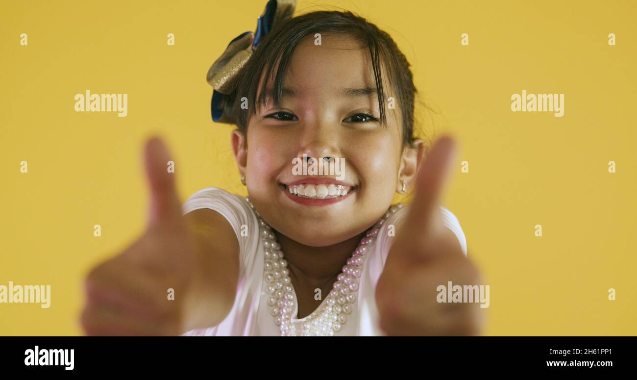 Beautiful asian girl sitting on yellow background. Happy little Asian ...