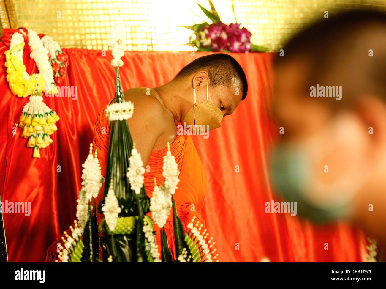 A Buddhist monk wearing a face mask stands next to a red cloth during ...