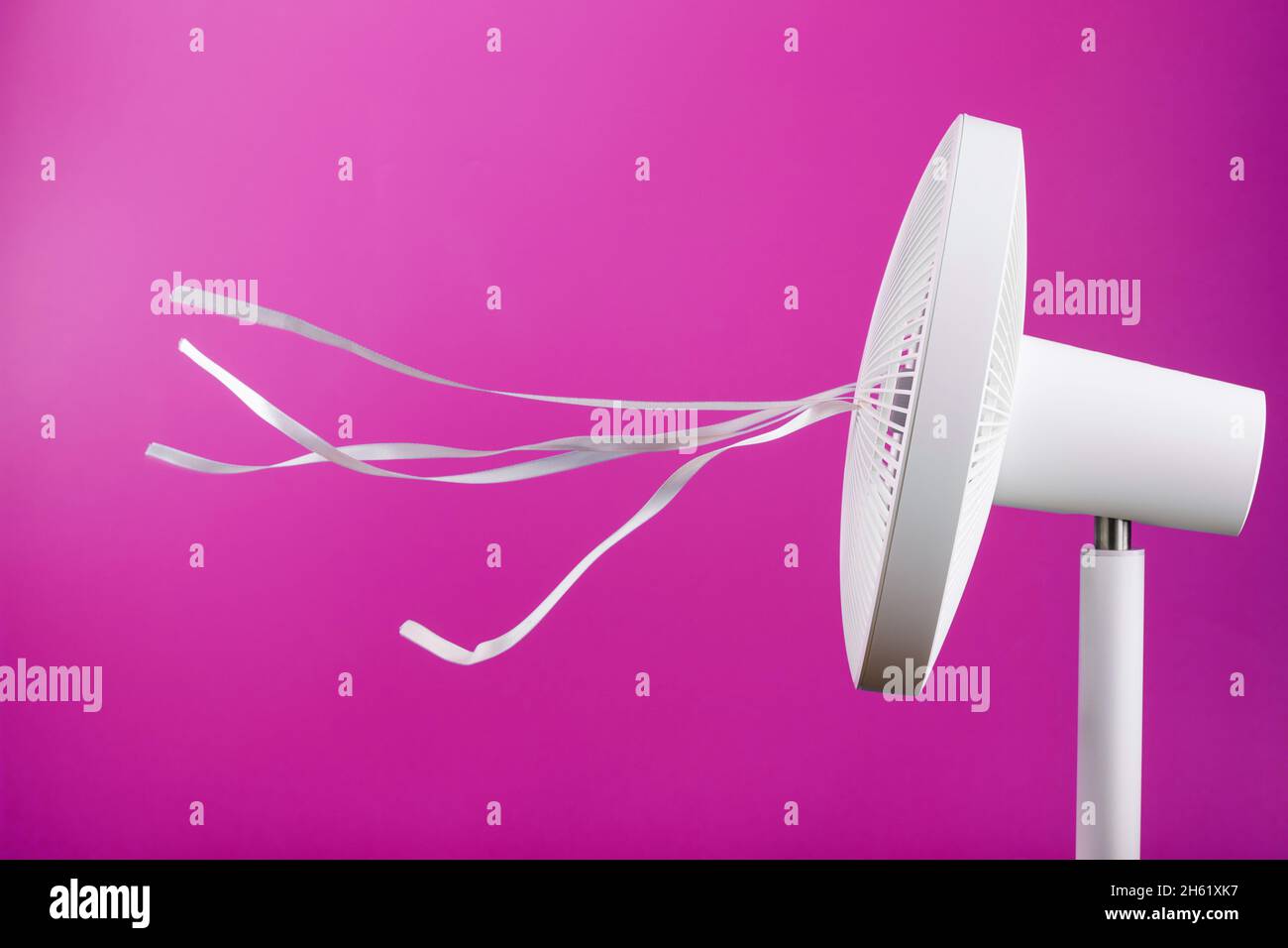 The electric fan is white with pink ribbons fluttering in the wind on a ...