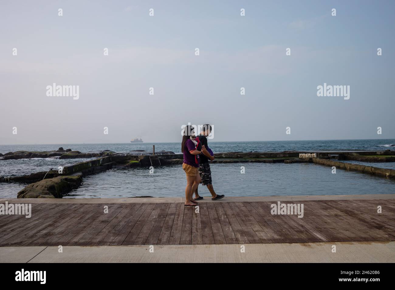 couple walks cat at seaside outdoor swimming pool in heping island park ...