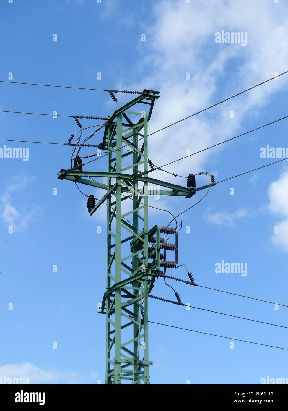 Vertical shot of an electricity pylon with lines on a blue sky ...