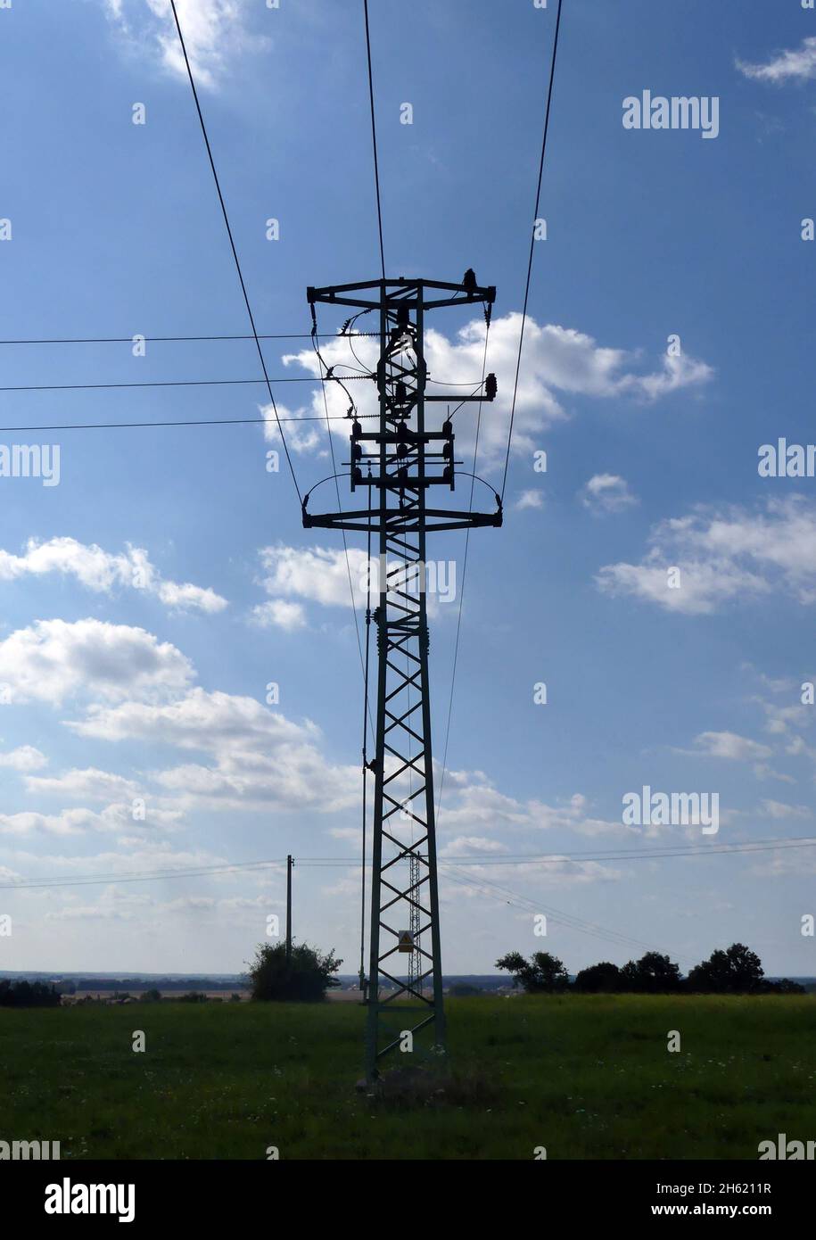 Vertical shot of an electricity pylon with lines on a blue sky ...