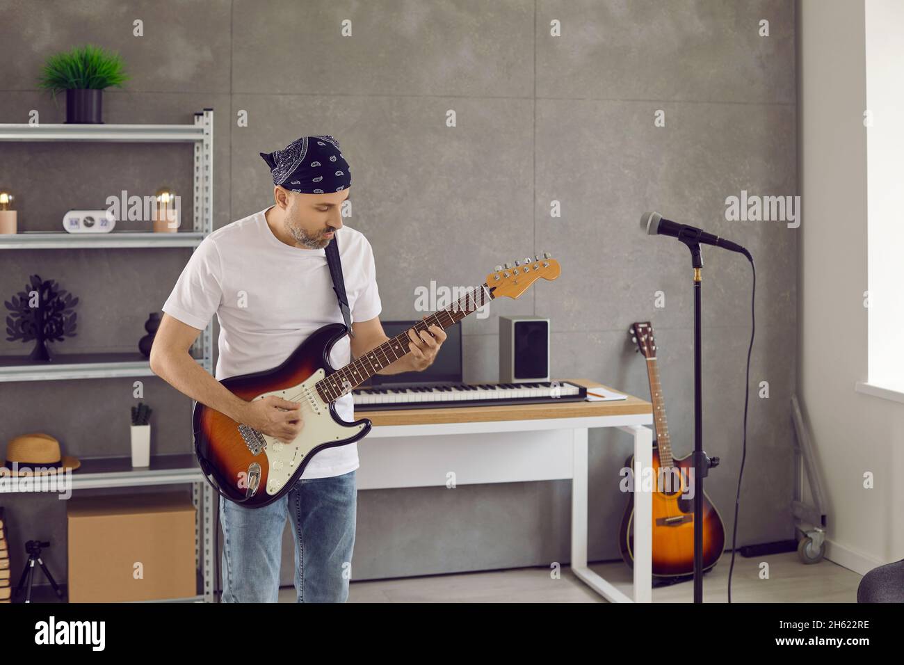 Focused and enthusiastic adult rocker man playing electric guitar in ...