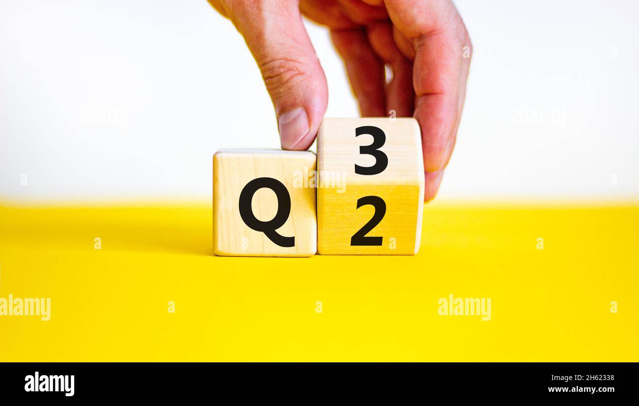 From 2nd to 3rd quarter symbol. Businessman turns a wooden cube and ...