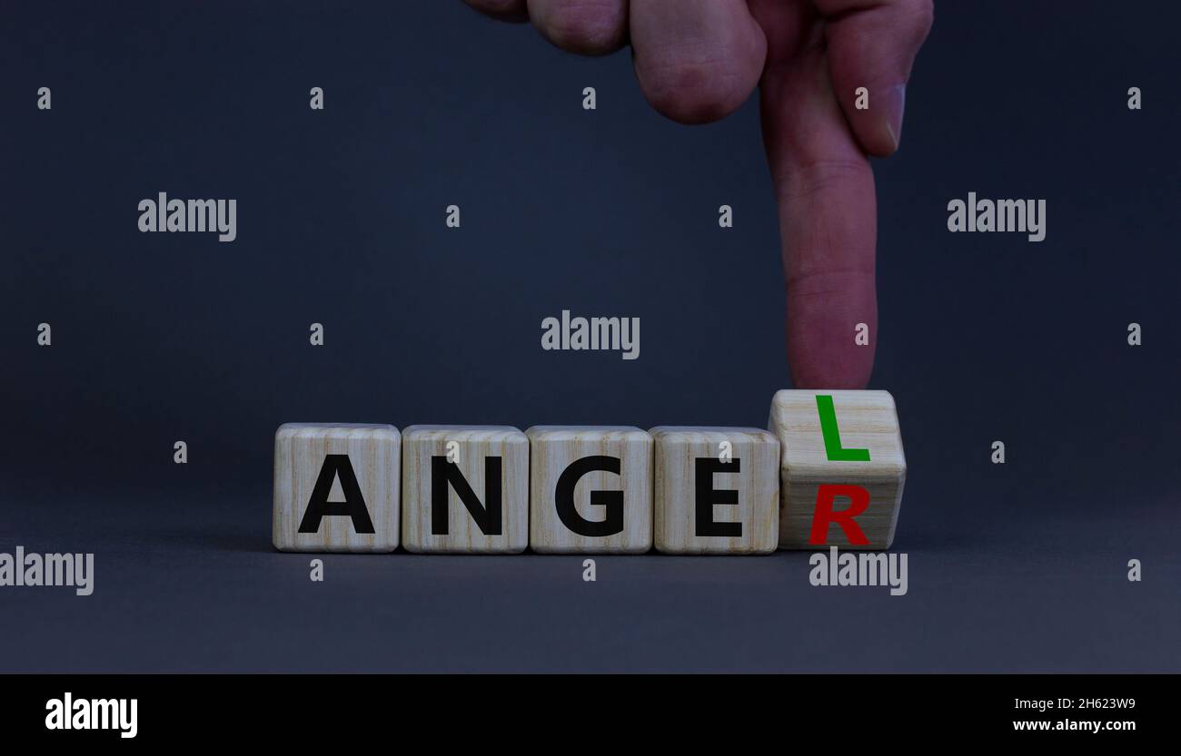 Having anger or being an angel. Businessman turns a wooden cube and ...