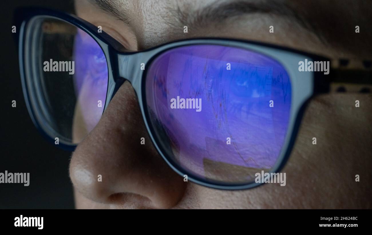 Close-up portrait of a caucasian woman in glasses looks at the screen ...