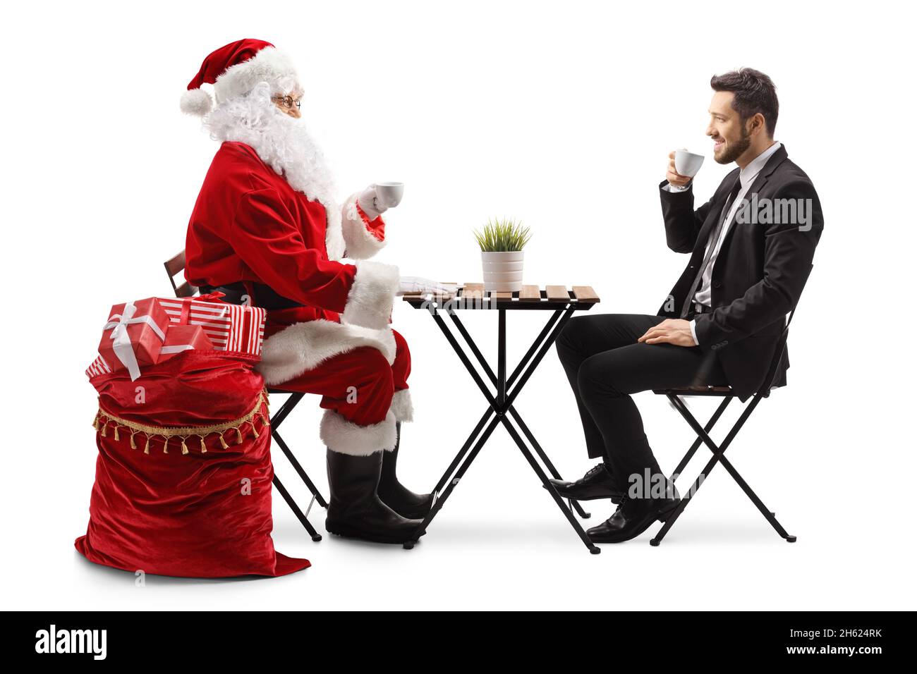 Santa Claus drinking coffee with a businessman at a cafe table isolated ...