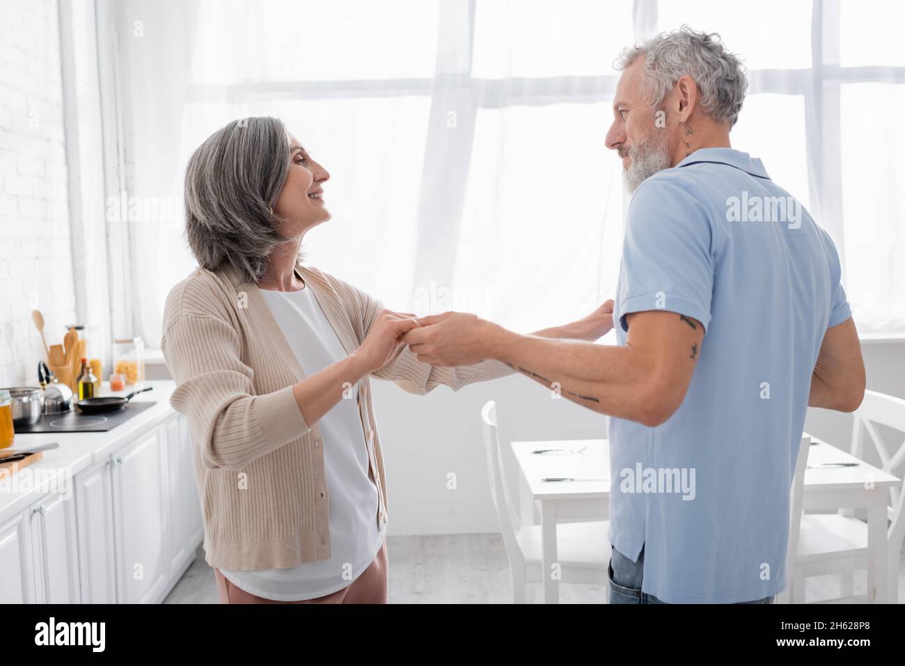 Side view of smiling middle aged couple dancing in kitchen Stock Photo ...