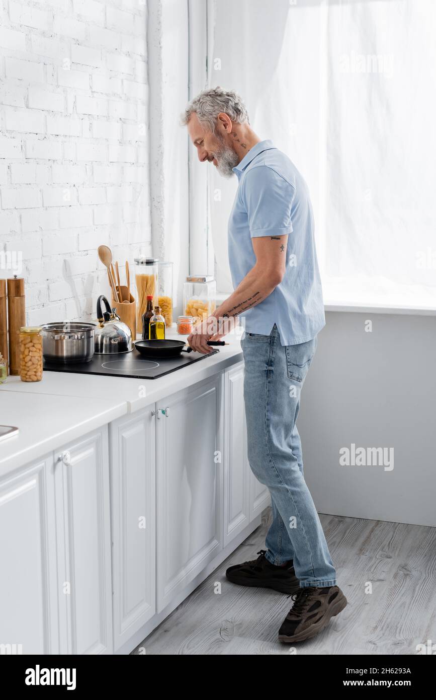 Side view of man cooking on stove near food on kitchen worktop Stock ...