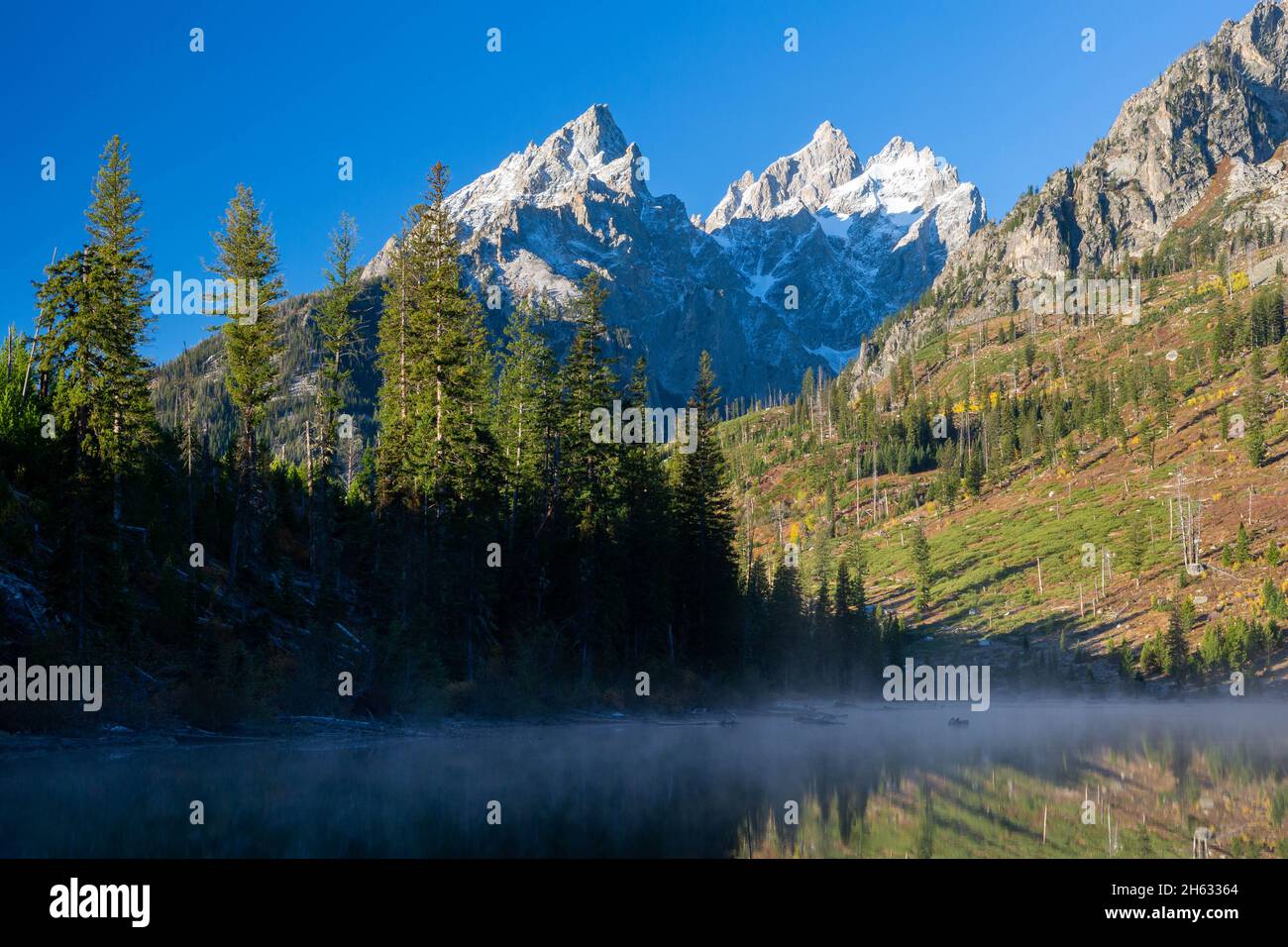 The Cathedral Group of Teton Peaks rising high above the calm waters of ...