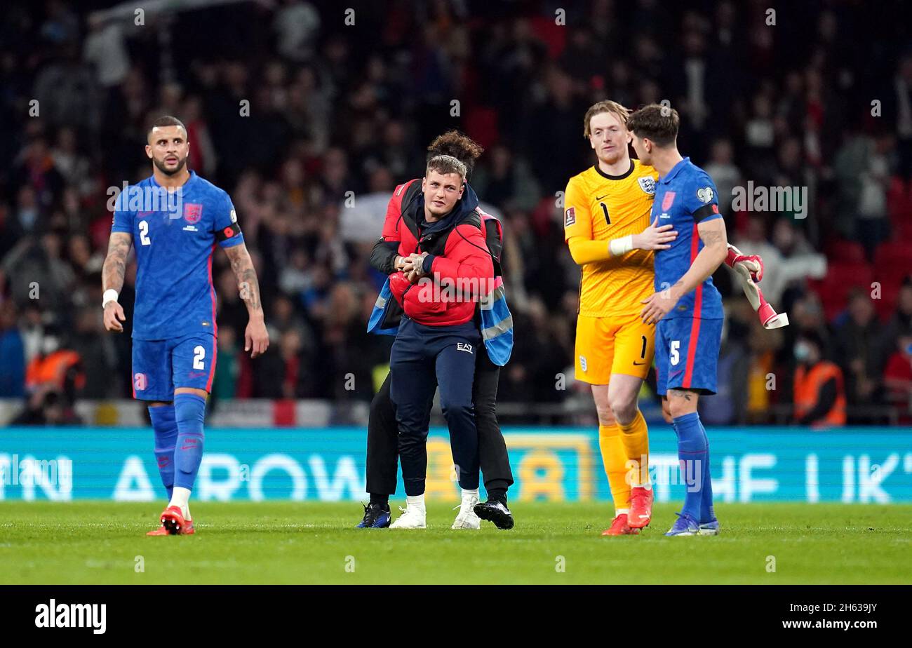 A pitch invader is stopped by stewards from approaching the players ...