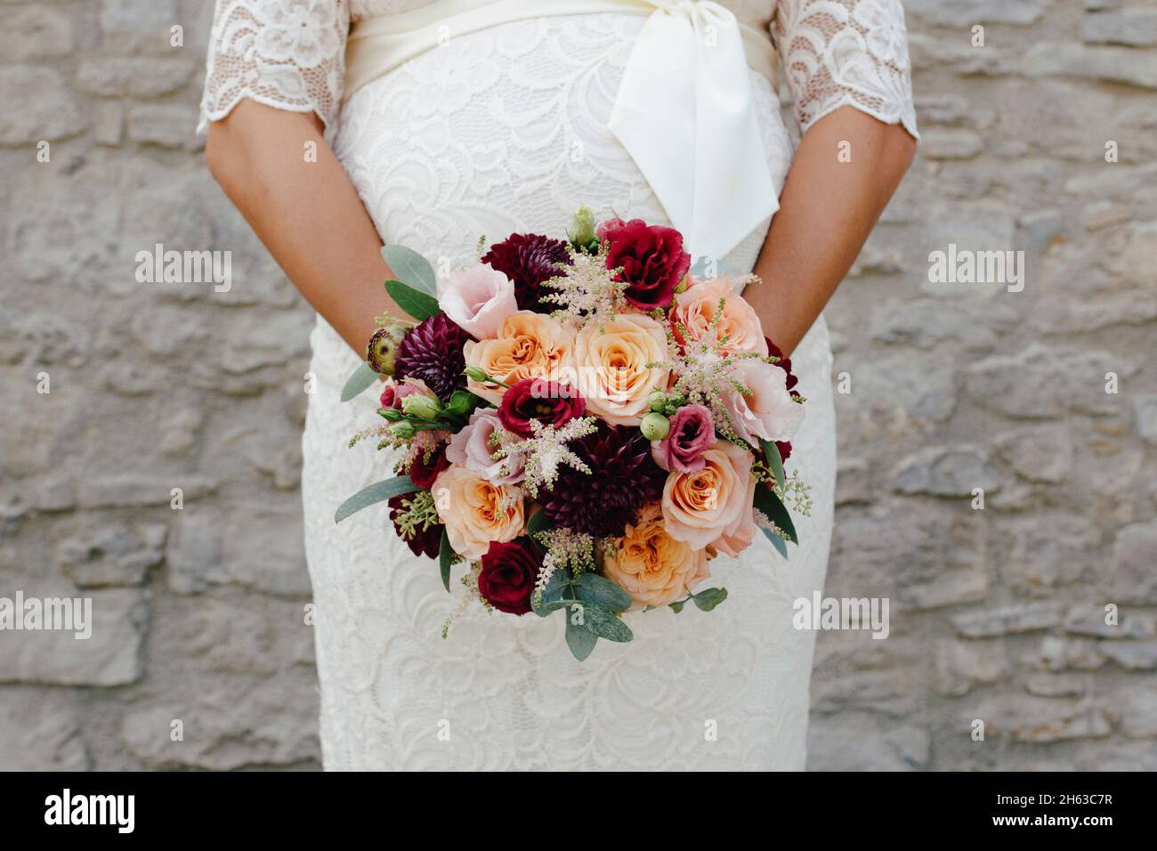pregnant bride in a white lace dress with a colorful bridal bouquet in ...