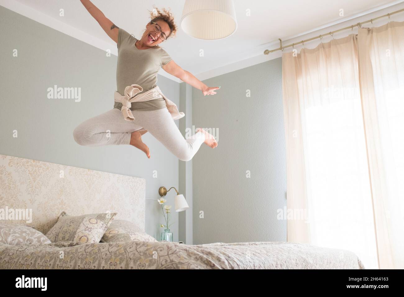 young adult pretty woman go crazy for happiness and jump on the bed ...