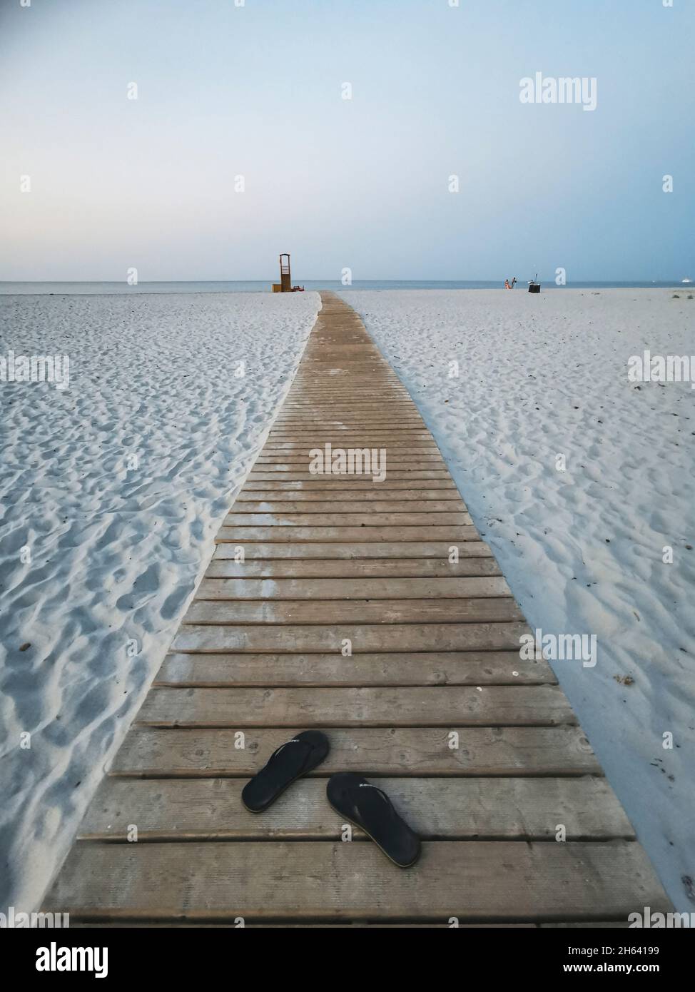long wooden path on the white beach sand to sea water with pair of ...