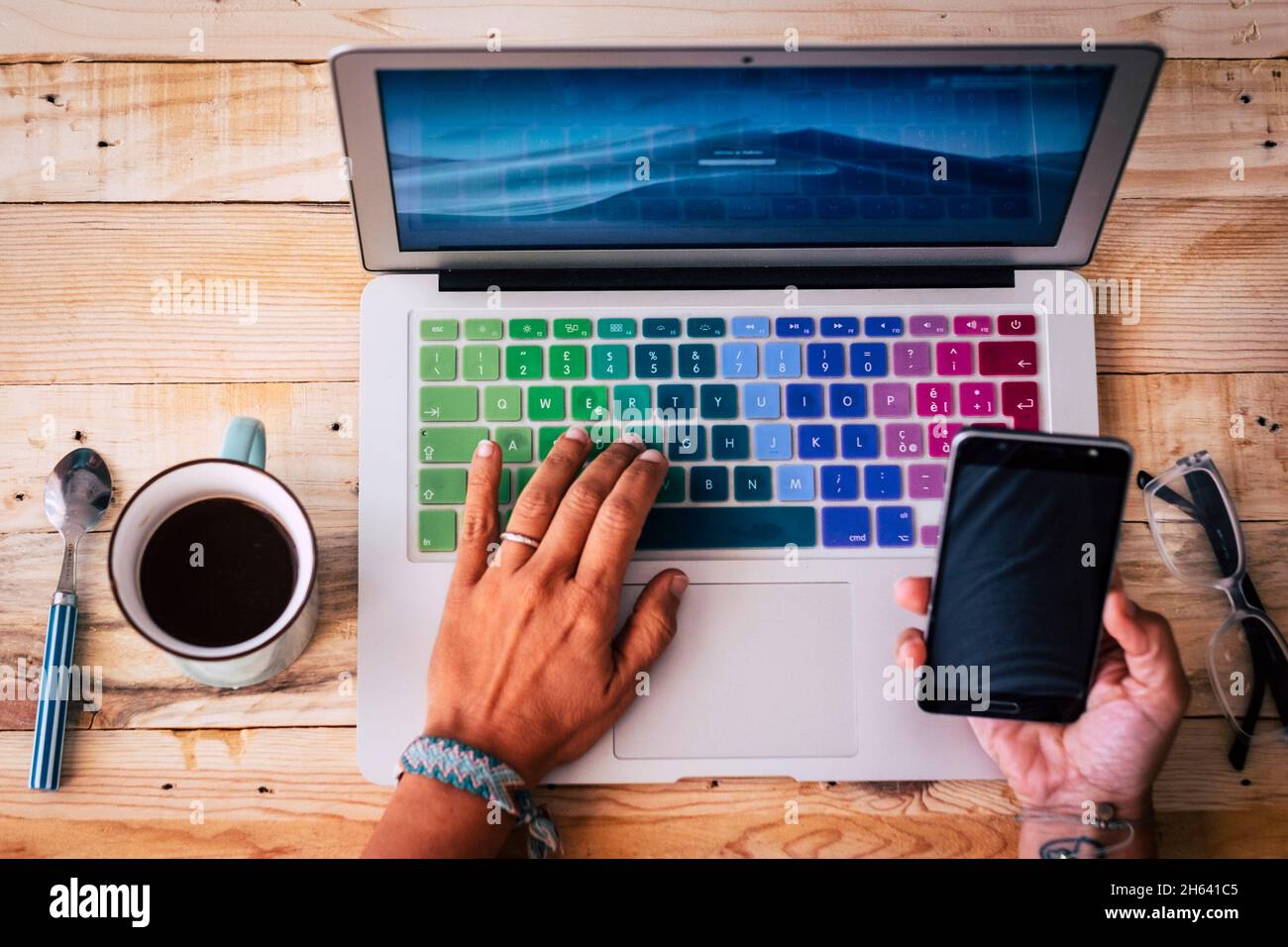 above view of desktop workstation with woman hands connecting phone to ...
