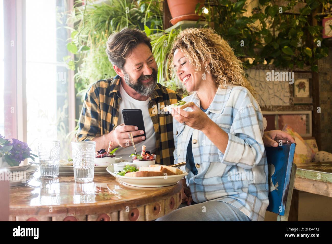 adult couple smile and enjoy lunch and phone video call sitting at the ...