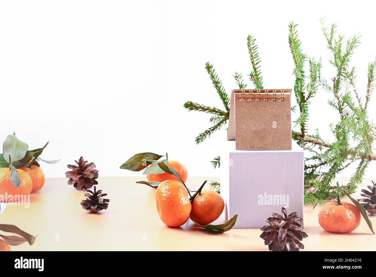 Christmas composition with spruce, tangerines, podium and notepad. Soft ...