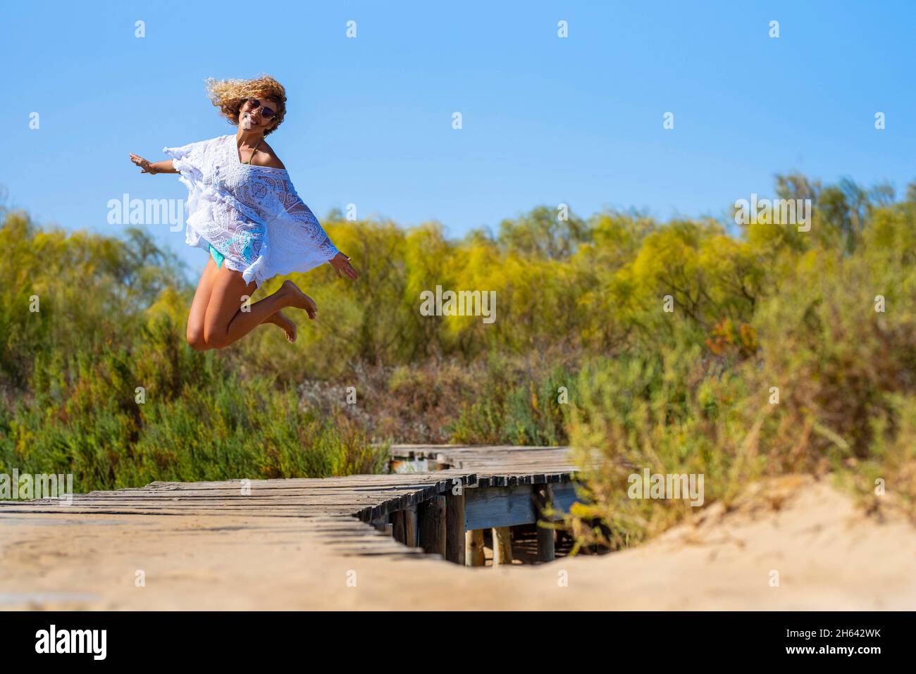 carefree woman jumping barefoot in air on elevated footbridge leading ...